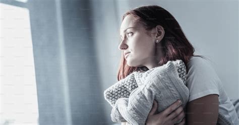 그의 존재 우울한 유쾌한 슬픈 여자는 옆모습으로 얼굴을 돌리고 흐릿한 배경에 앉아 베개를 들고 포즈를 취하고 있다 사진