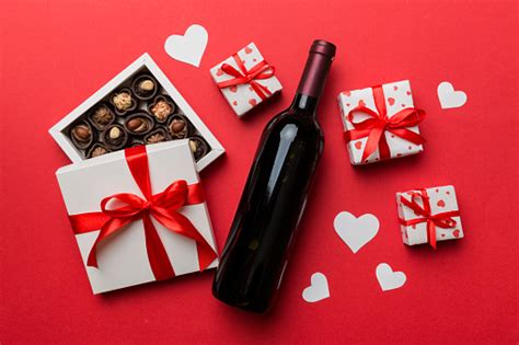 선물과 초콜릿 발렌타인 데이에 대한 컬러 배경에 레드 와인 병 복사 공간이있는 초콜릿 탑 뷰의 선물 상자가있는 하트 모양 선물에
