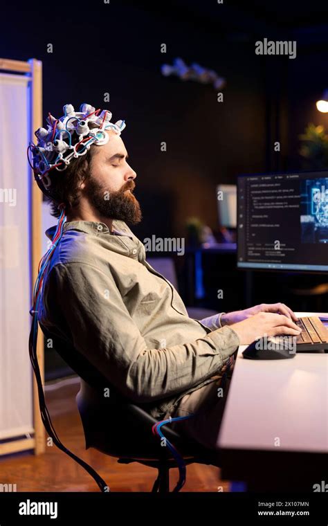 Man With Eeg Headset On Typing On Keyboard Writing Code Allowing Him To Transfer Mind Into