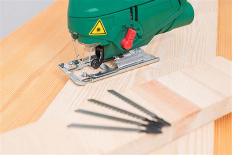 한 남자가 장갑을 끼거나 낀 채 나무 테이블에서 퍼즐과 드라이버로 작업하고 줄자로 측정합니다 0명에 대한 스톡 사진 및 기타