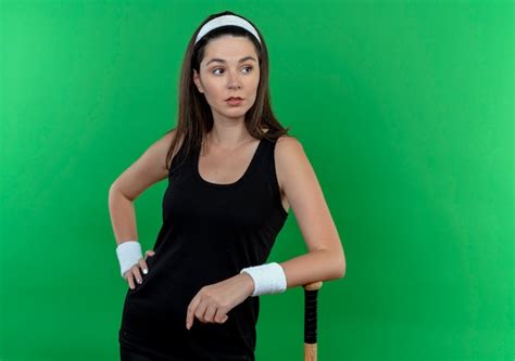Free Photo Young Fitness Woman In Headband Leaning Her Hand On Baseball Bat Looking Aside