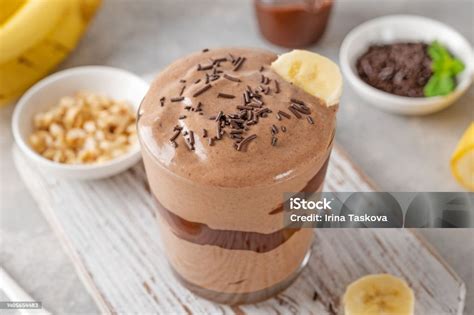 초콜렛 유약을 곁들인 비건 바나나 초콜릿 아이스크림을 회색 콘크리트 배경에 유리에 뿌린다 건강 식품 공간을 복사합니다 스무디에