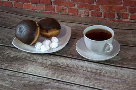 접시에 홍차 한 잔과 초콜릿 장식 및 Bize의 조각에 두 개의 도넛과 접시 벽돌 벽에 대 한 나무 테이블에 누워 있습니다 커피 휴식 클로즈업 0명에 대한 스톡 사진 및