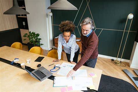 사무실의 팀워크는 창업 투자 계획을 개발하는 다양한 사업가들입니다 사무실에서 일하는 수석 고문 및 젊은 다인종 직원 투자에 대한 스톡 사진 및 기타 이미지 Istock