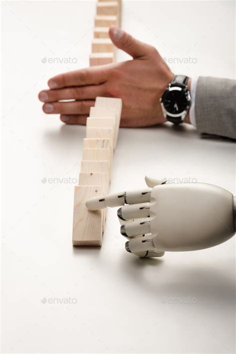 Cropped View Of Robotic Hand Pushing Wooden Bricks While Man Preventing Row From Falling Stock