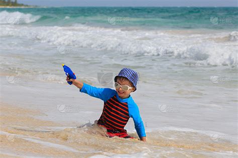 小男孩在海滩上玩水枪