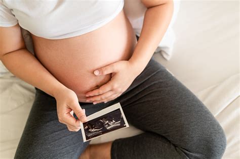 임신 한 여자는 그녀의 아이를 돌보는 동안 집에서 행복 느낌 임신 뱃속에서 아기를 안고 있는 어머니를 기다리는 젊은 출산 태아