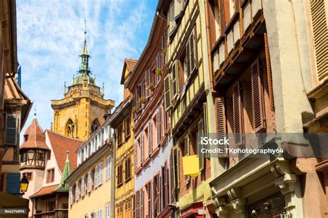 아름 다운 오래 된 골조 전선 주거 건물 및 화려한 셔터는 아름 다운 오래 된 프랑스 마을 콜마르 알자스에 있는 배경에서 대성당의 좋은 보기의 보기 0명에 대한 스톡 사진