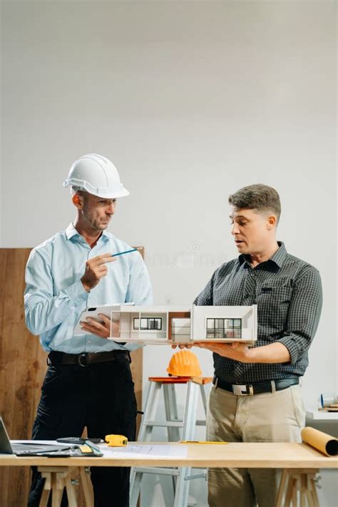 Professional Collaboration In Architecture Two Engineers Work On Construction Plans Using