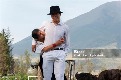 원주민 문화의 전통 의상을 입은 원주민 남성이 화산을 배경으로 한 시골 환경에서 아내를 다정하게 포옹합니다 그의 표정은 따뜻함과 보살핌을 전달하며 가족 유대의 순간을