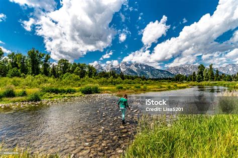 Girl Crosses A River While Hiking In Scenic Grand Teton National Park
