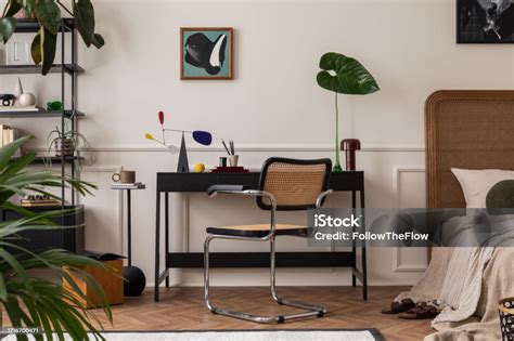 모형 포스터 프레임 검은 책상 아늑한 침대 나뭇잎이 달린 꽃병 등나무 의자 현대 조각품 치장 벽토 벽 및 개인 액세서리가 있는