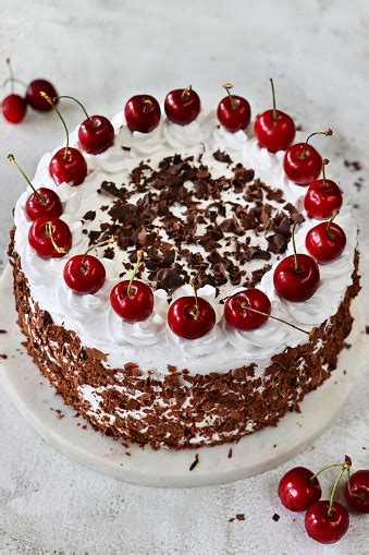 케이크 스탠드에 블랙 포레스트 가토의 이미지 모렐로 체리를 얹은 파이프 휘핑 크림 로제트 휘핑 크림으로 서리가 내린 고급 초콜릿 케이크 초콜릿 면도 대리석 효과 배경 높은