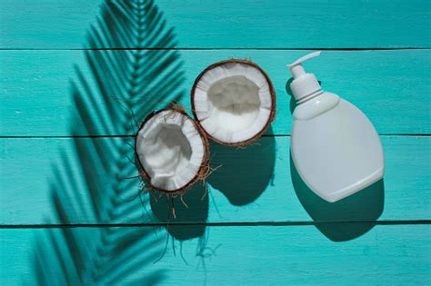 미니멀 한 아름다움 은 여전히 생활 파란 나무 배경에 야자수 잎에서 그림자와 다진 코코넛과 크림의 흰색 병의 두 반쪽 크리에이티브 패션 컨셉 맨 위 보기 건강한 생활방식에