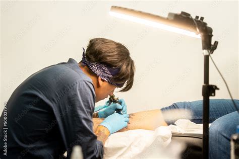 Tattooist Making Tattoo On Leg Of Client Stock Photo Adobe Stock