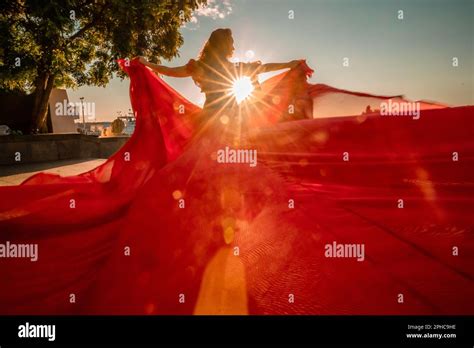 Sunrise Red Dress A Woman In A Long Red Dress Against The Backdrop Of