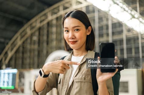 여행자 젊은 아시아 여성 터미널 기차역에서 휴대 전화 예약 여행을 사용 스마트 폰 검색 위치를 사용하여 기차로 행복한 관광 여행 여성 백패커가 플랫폼 철도에 도착합니다
