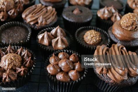 파이프 초콜릿 아이싱 프로스팅 금속 냉각 랙에 다크 페이퍼 케이크 케이스를 얹은 홈메이드 초콜릿 컵케이크의 클로즈업 이미지 슬레이트 배경 전경에 초점 0명에 대한 스톡 사진
