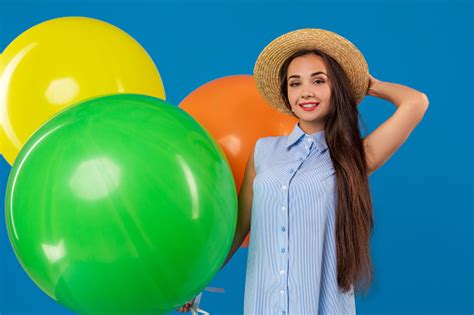 오렌지 노랑 녹색 풍선을 들고 스튜디오에 귀여운 갈색 머리 서 그녀는 밝은 파란색 드레스를 착용 하 고 길고 물결 모양 머리카락을가지고 갈색 머리에 대한 스톡 사진 및 기타