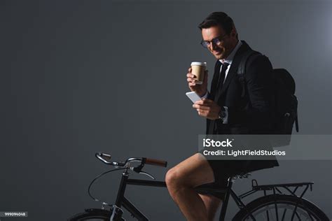 세련 된 남자 손에 스마트폰으로 자전거에 앉아와 회색 배경에 커피를 마시는 배낭 남자에 대한 스톡 사진 및 기타 이미지 남자 남자들만 두발자전거 Istock