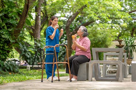건강 관리 또는 물리 치료 간호사는 노인이 편안하게 보이고 아이스크림을 먹고 운동에 참여하고 일상적인 간병인 재활 운동에 중점을 둔 개인 노인 개념을 돕습니다 2명에 대한