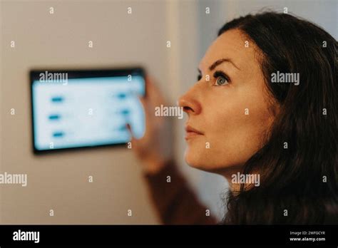 Mature Woman Controlling Temperature Of Room Through Digital Tablet At