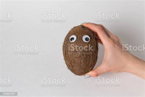 손은 흰색 배경에 끈적 거리는 눈으로 코코넛을 보유하고 있습니다 재미있는 얼굴을 가진 코코넛 캐릭터 건강한 생활방식에 대한 스톡