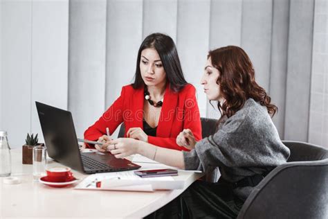 Two Stylish Girls Designers Are Working With Laptop And Documentation At The Project Sitting At