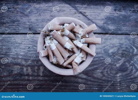 Overflowed Ashtray With Cigarette Butts On A Wooden Window Sill In The