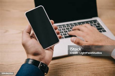 직장에서 노트북에 입력 하는 동안 스마트폰 들고 사업가의 자른된 보기 기업 비즈니스에 대한 스톡 사진 및 기타 이미지 기업 비즈니스 남성 남자 Istock