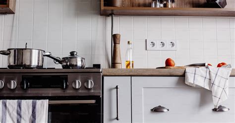 강철 오븐 냄비 야채 후추 향신료 나무 테이블 위에 기름을 곁들인 나무 도마에 칼이 있는 현대적인 주방에서 음식을 요리합니다 가정 음식 그레이 색상의 세련된