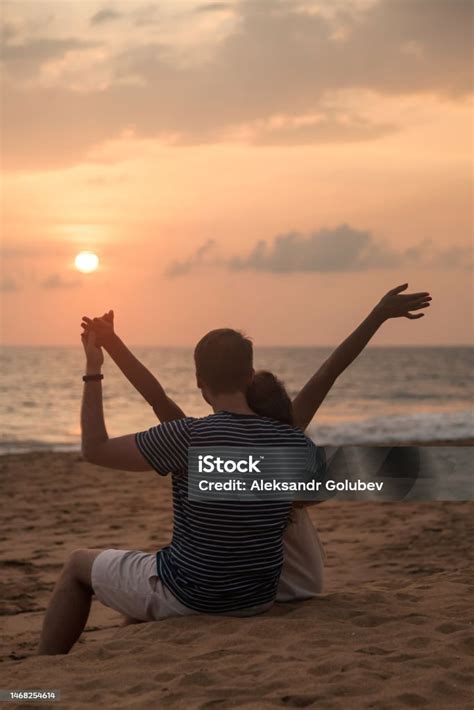 일몰 배경의 열대 모래 해변에서 신혼 여행 여름을 즐기는 사랑에 빠진 뒷모습 커플 행복 한 사랑스러운 커플 뒤에서 팔을 올렸다 가족 여행 휴가 개념입니다 광고문안 공간 복사