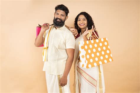 전통 드레스를 입고 쇼핑백을 들고 베이지색 배경에 고립된 축제를 함께 축하하는 행복한 남인도 커플 축제 시즌 판매 복사 공간 패션에 대한 스톡 사진 및 기타 이미지 Istock