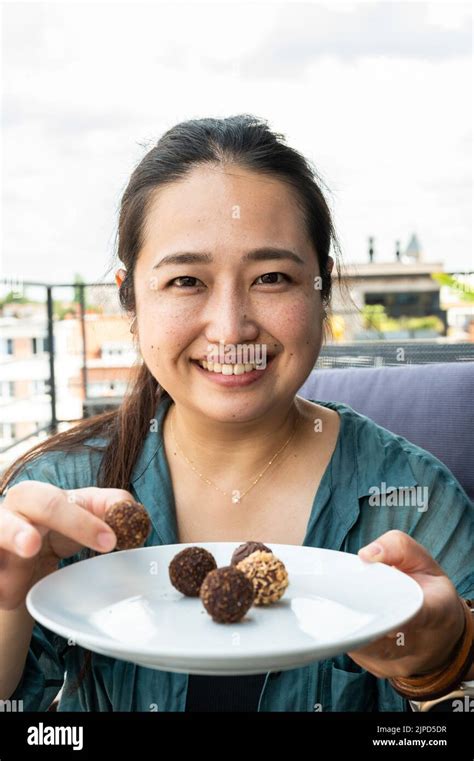 Portrait Of A 32 Year Old Japanese Woman Holding A Plate Of Round