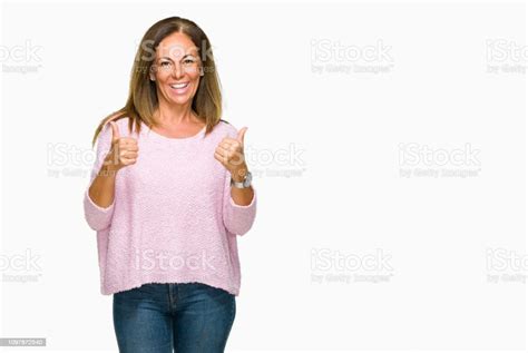 아름 다운 중 년 성인 여자 손으로 긍정적인 제스처를 하 고 격리 된 배경 성공 기호 이상의 겨울 스웨터를 입고 웃 고 행복 한 엄지 쾌활 한 식 우승자 제스처와 카메라를