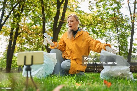 공원에서 쓰레기를 수집하는 동안 스마트 폰에서 자신의 블로그를 녹음하는 소녀 Brand Name Smart Phone에 대한