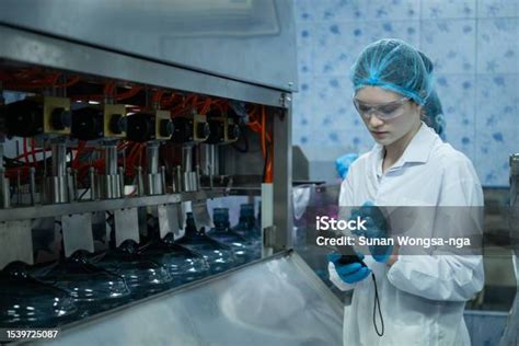 흰 코트와 파란 모자를 쓴 여성 과학자는 생산 라인의 제어 기계에서 일하고 있다 검사 보기에 대한 스톡 사진 및 기타 이미지 검사 보기 검사자 공장 산업 건물