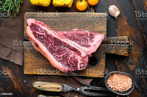 건조 숙성 Raw T 뼈 또는 포터 하우스 대리석 쇠고기 고기 스테이크 허브와 향신료 오래 된 어두운 나무 테이블 배경에 상단 보기 플랫 누워 0명에 대한 스톡 사진 및