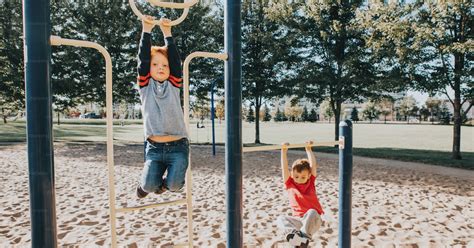 어린 백인 소년 친구들은 놀이터 공원의 원숭이 바와 풀업 바에 매달려 있습니다 아이들을위한 여름 야외 활동 활동적인 아이들은 운동 스포츠를합니다 건강한 행복한 어린