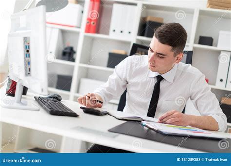 A Young Man Sitting At A Computer Desk In The Office And Working With