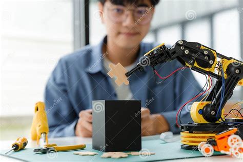 Asian Teenager Constructing Robot Arm Project In Science Classroom