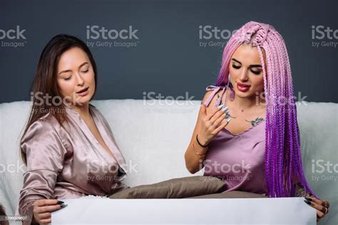 소파에 집에서 현대 여자는 아래를 보고 광고가 될 수있는 흰색 포스터를 개최 회색 배경 땋은 머리에 대한 스톡 사진 및 기타 이미지 땋은 머리 2명 가정의 방