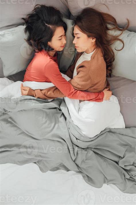 Young Lesbian Women In Love Embracing While Lying Don On Bed At Home