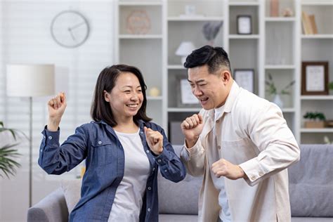 행복한 아시아 커플 남자와 여자는 거실에서 낮에 집에서 함께 춤을 추고 행복한 날과 결혼 기념일을 축하하는 행복한 젊은 가족 양 부모에 대한 스톡 사진 및 기타 이미지