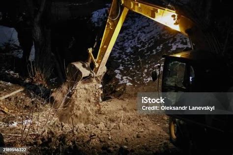 굴착기 로더는 건설 현장에서 밤에 흙을 파고 흙은 건설 현장 조명에서 건설 현장에서 굴삭기 버킷에서 쏟아져 나옵니다 건설 기계류에 대한 스톡 사진 및 기타 이미지 Istock