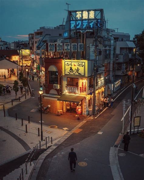 A Man Walking Down The Street At Night