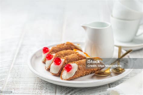 체리를 얹은 리코타 치즈 크림을 곁들인 이탈리아 페이스트리 카놀리와 함께 조식을 즐겨보냅니다 배경에 커피 컵 흰색 나무 표면 공간을 복사합니다 카놀리에 대한 스톡 사진 및