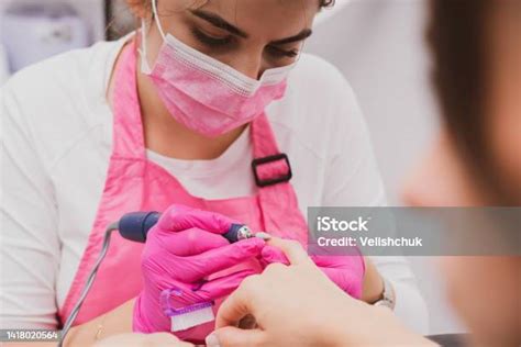 매니큐어 살롱 마스터는 매니큐어를 제거하고 전기 네일 파일을 사용합니다 손톱 매니큐어를 얻는 여자 뷰티 살롱의 전문 매니큐어 위생 및 손 관리 뷰티 산업 개념 20 24세에