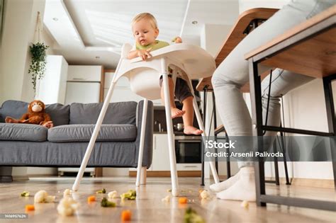 높은 의자에 앉아 찐 야채로 덮인 지저분한 바닥을 바라 보는 아기의 측면보기 유아용 식탁의자에 대한 스톡 사진 및 기타 이미지 유아용 식탁의자 지저분한 부엌 Istock