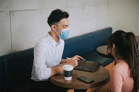 아시아 의 젊은 사업가가 질병 예방을위한 얼굴 마스크로 새로운 정상을 관찰하는 카페에서 고객에게 투자 계획을 설명합니다 18